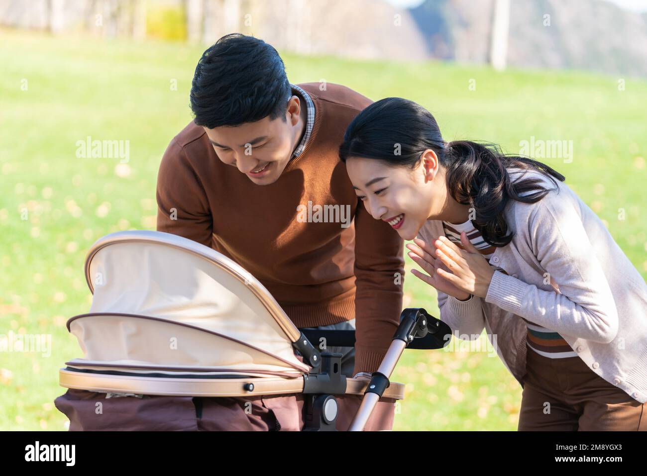 A young couple walk pushing a stroller Stock Photo - Alamy