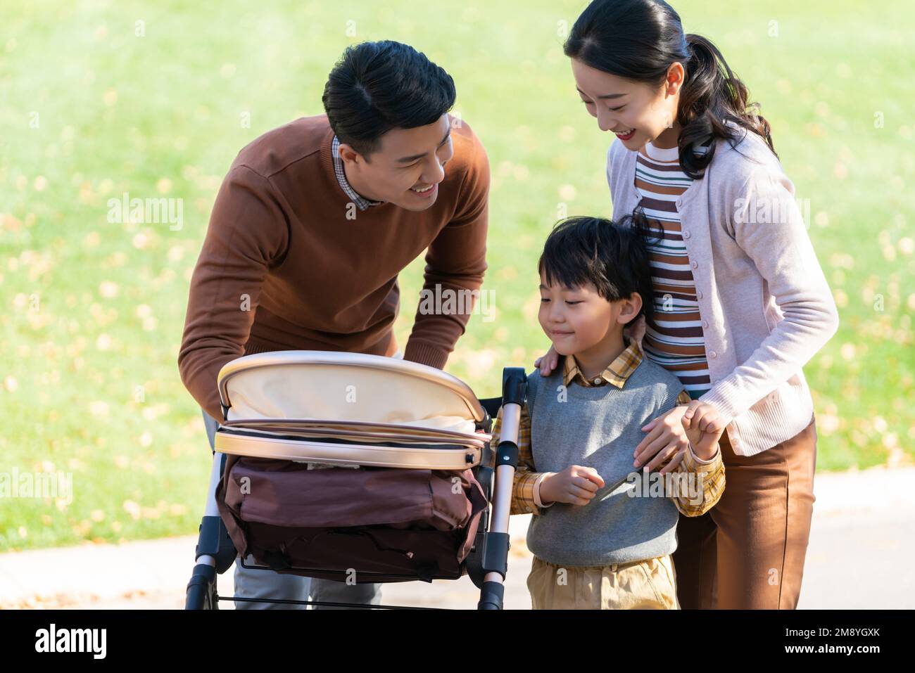 A young couple walk pushing a stroller Stock Photo - Alamy