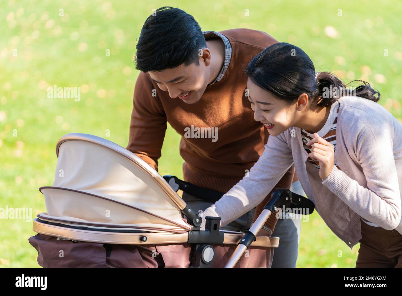 A young couple walk pushing a stroller Stock Photo - Alamy