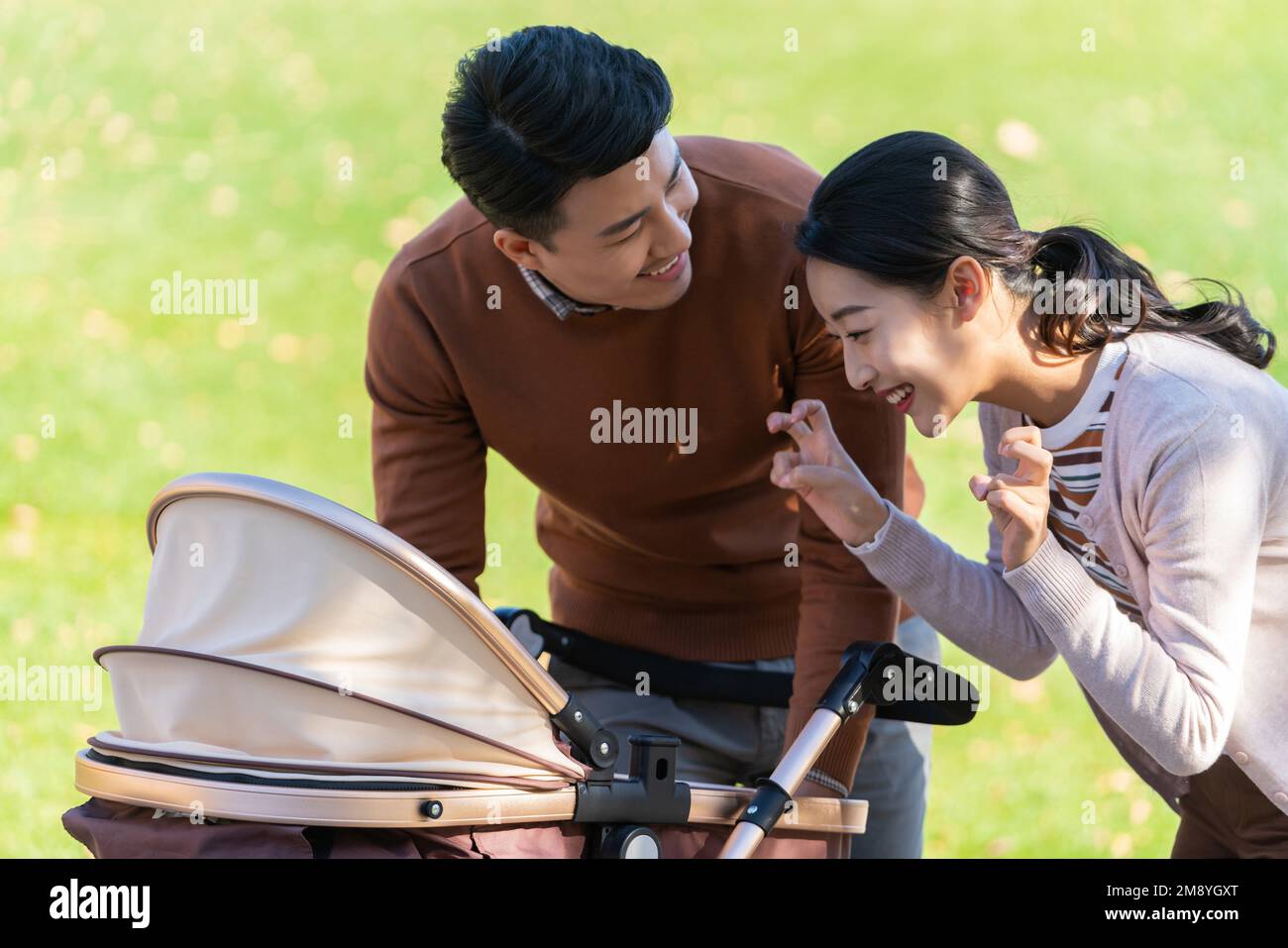 A young couple walk pushing a stroller Stock Photo - Alamy
