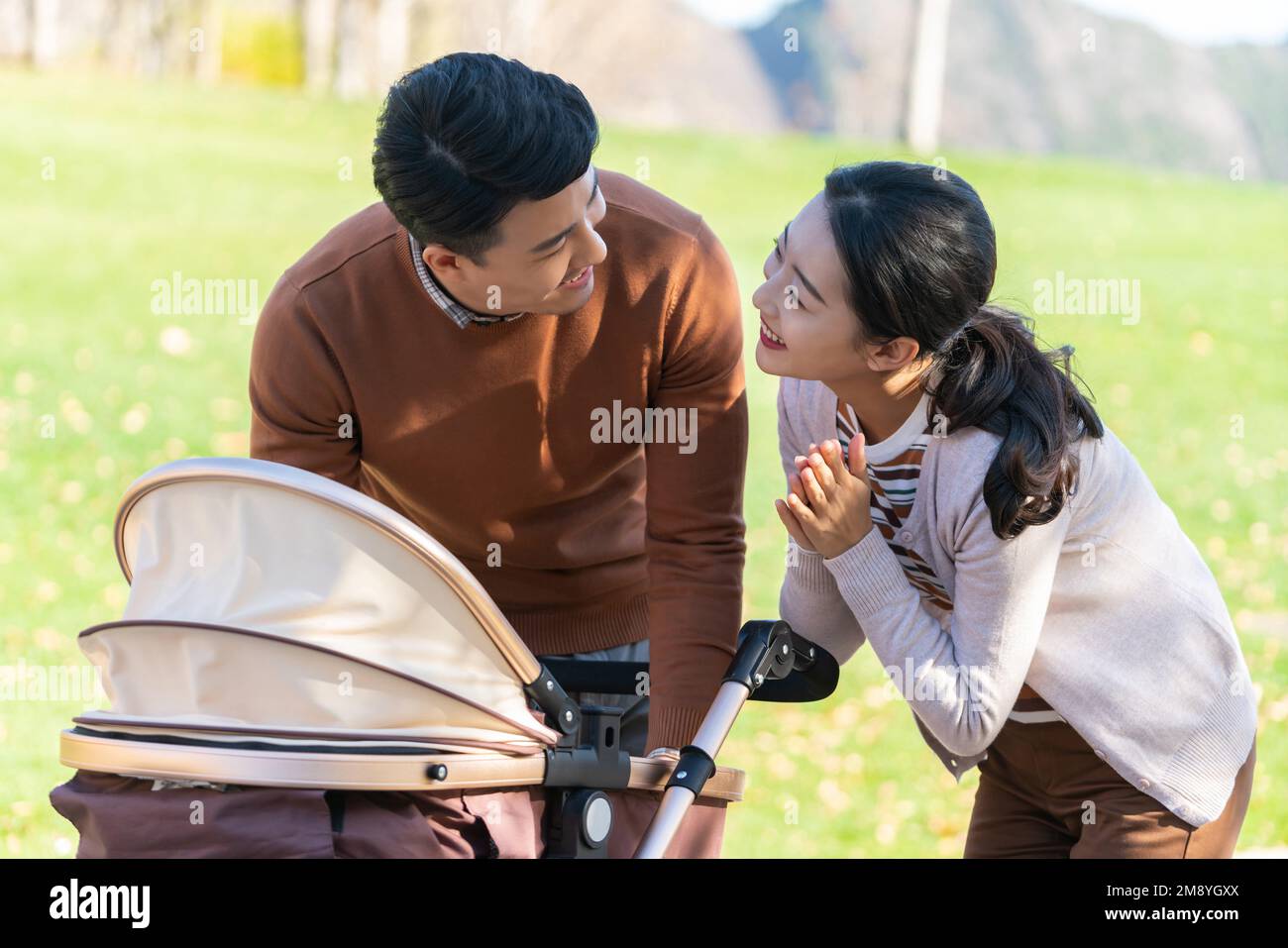 A young couple walk pushing a stroller Stock Photo - Alamy