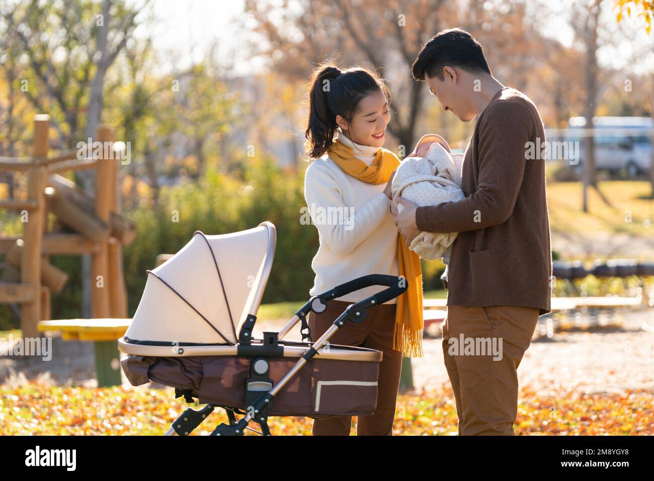 A young couple walk pushing a stroller Stock Photo - Alamy