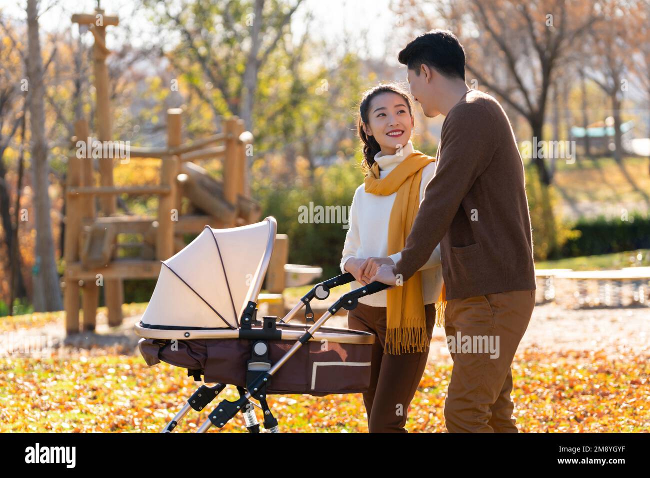 A young couple walk pushing a stroller Stock Photo - Alamy