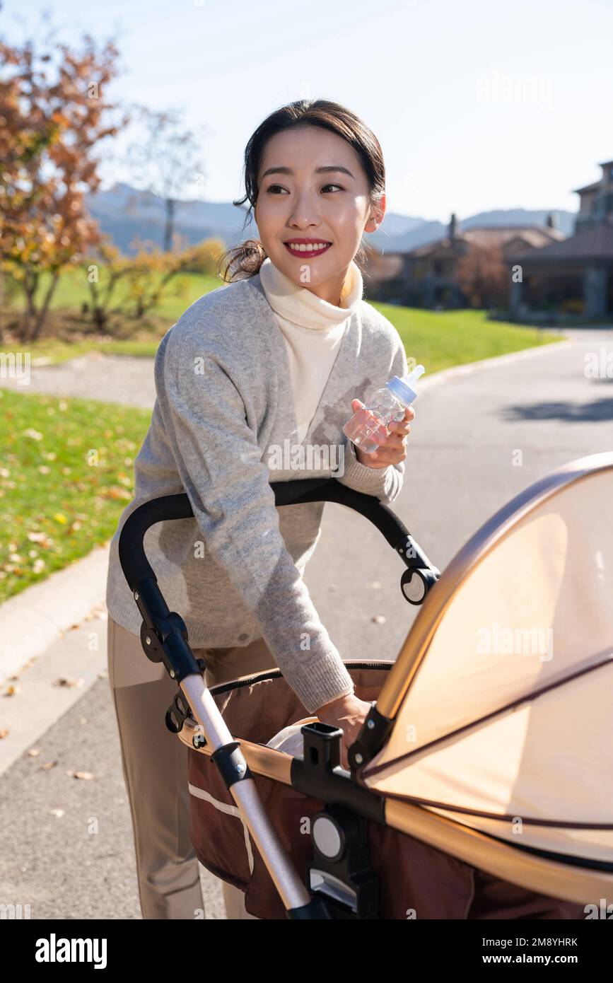 Young mother pushing a stroller for a walk Stock Photo - Alamy