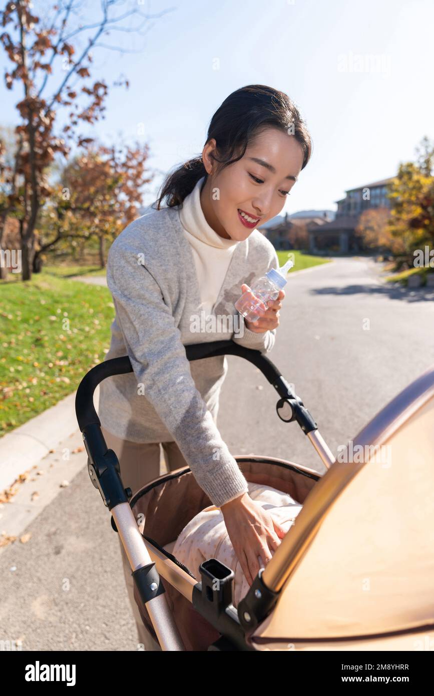 Young mother pushing a stroller for a walk Stock Photo - Alamy