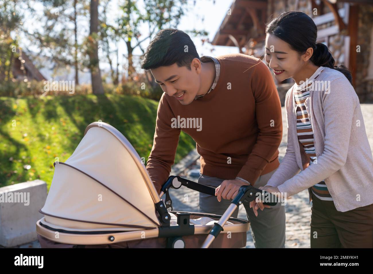 A young couple walk pushing a stroller Stock Photo - Alamy
