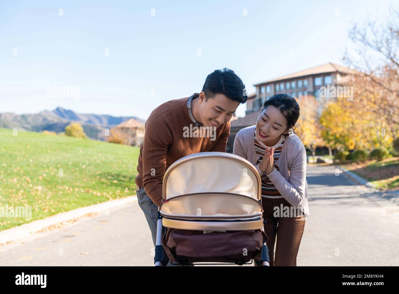 A young couple walk pushing a stroller Stock Photo - Alamy