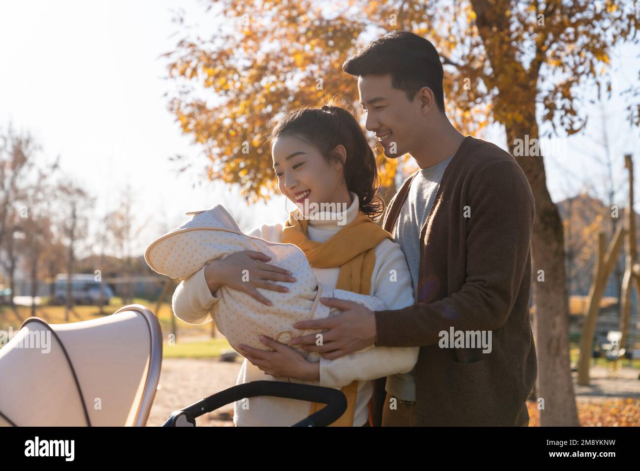 A young couple walk pushing a stroller Stock Photo - Alamy