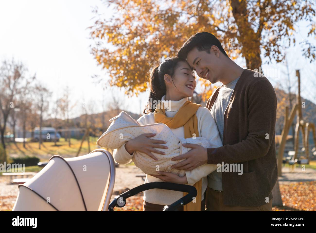 A young couple walk pushing a stroller Stock Photo - Alamy