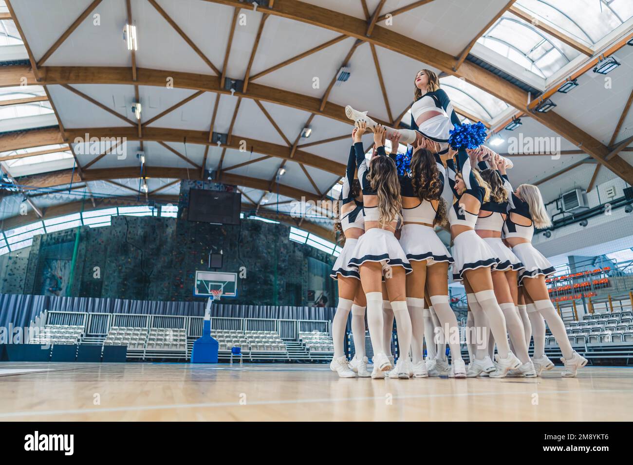 Full shot of a group of cheerleaders holding their teammate doing a ...