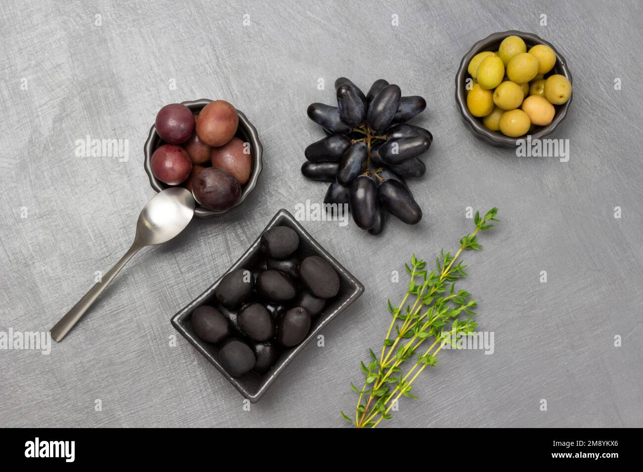 Green, red and black olives in bowls. Sprig of thyme and a bunch of ...