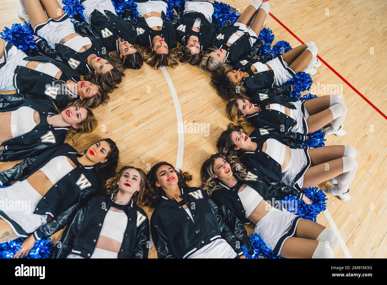 High angle shot. Cheerleading squad lying on the floor in a circle ...