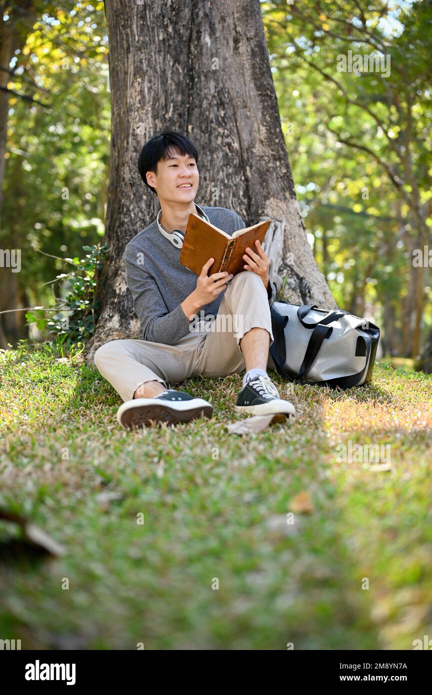 Portrait, Handsome and happy young Asian male college student reading a ...