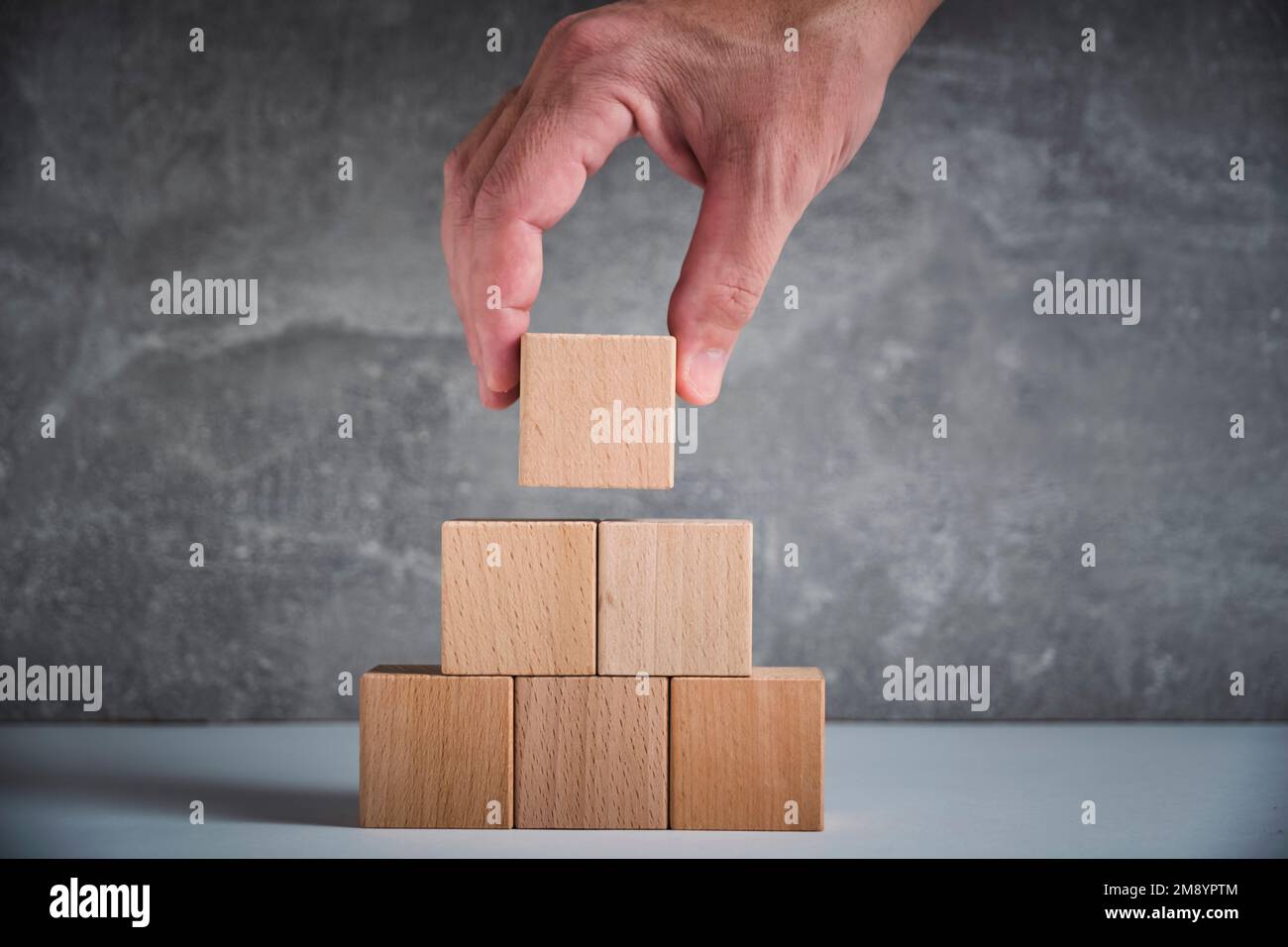 Laying out by hand a pyramid wooden cubes leading up.Concept growth and ...