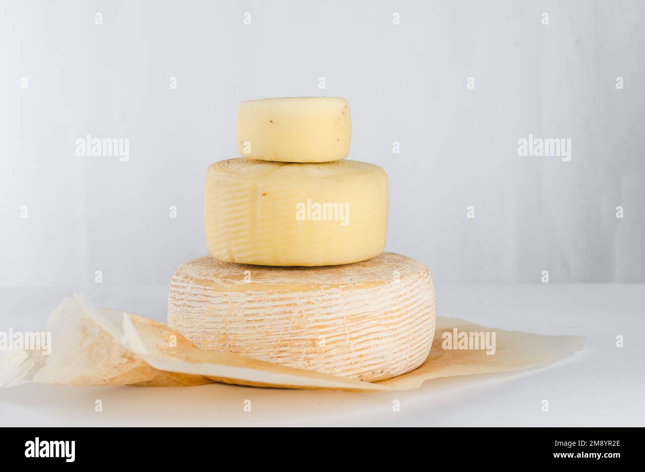 A pile of different kinds cheese heads stacked in vertical row on table ...