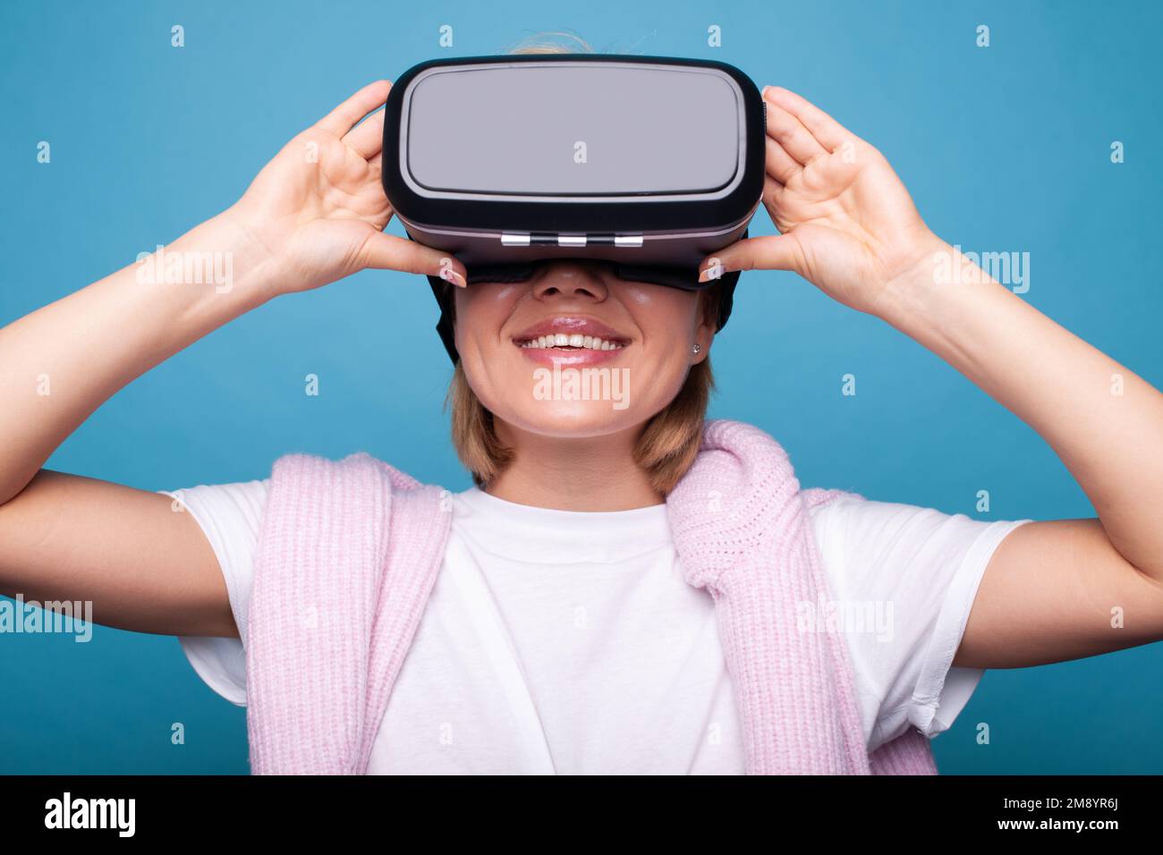 Young caucasian woman using VR headset, touching glasses and looking up ...