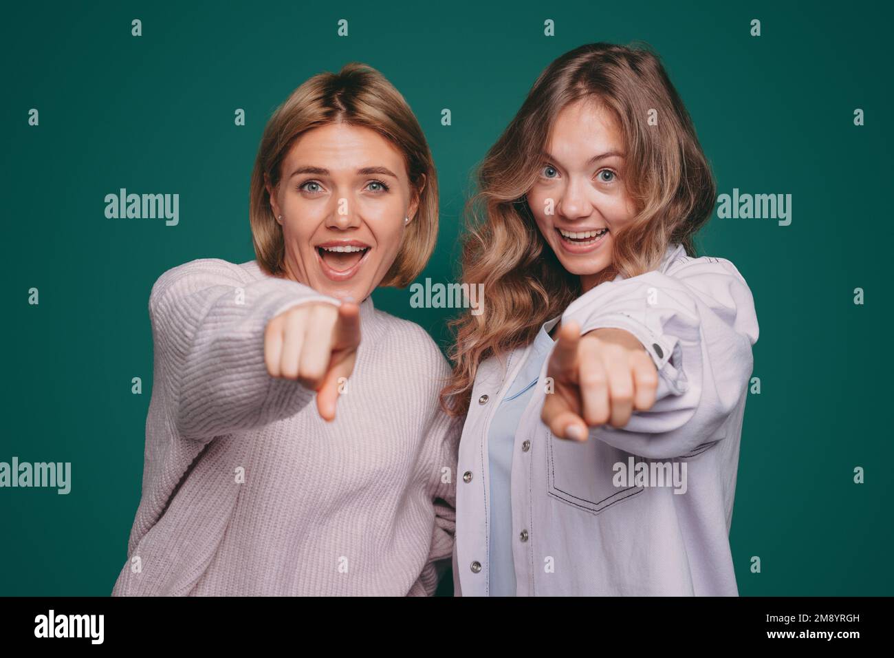 Fron view portrait of two sisters laughing out loud and pointing ...