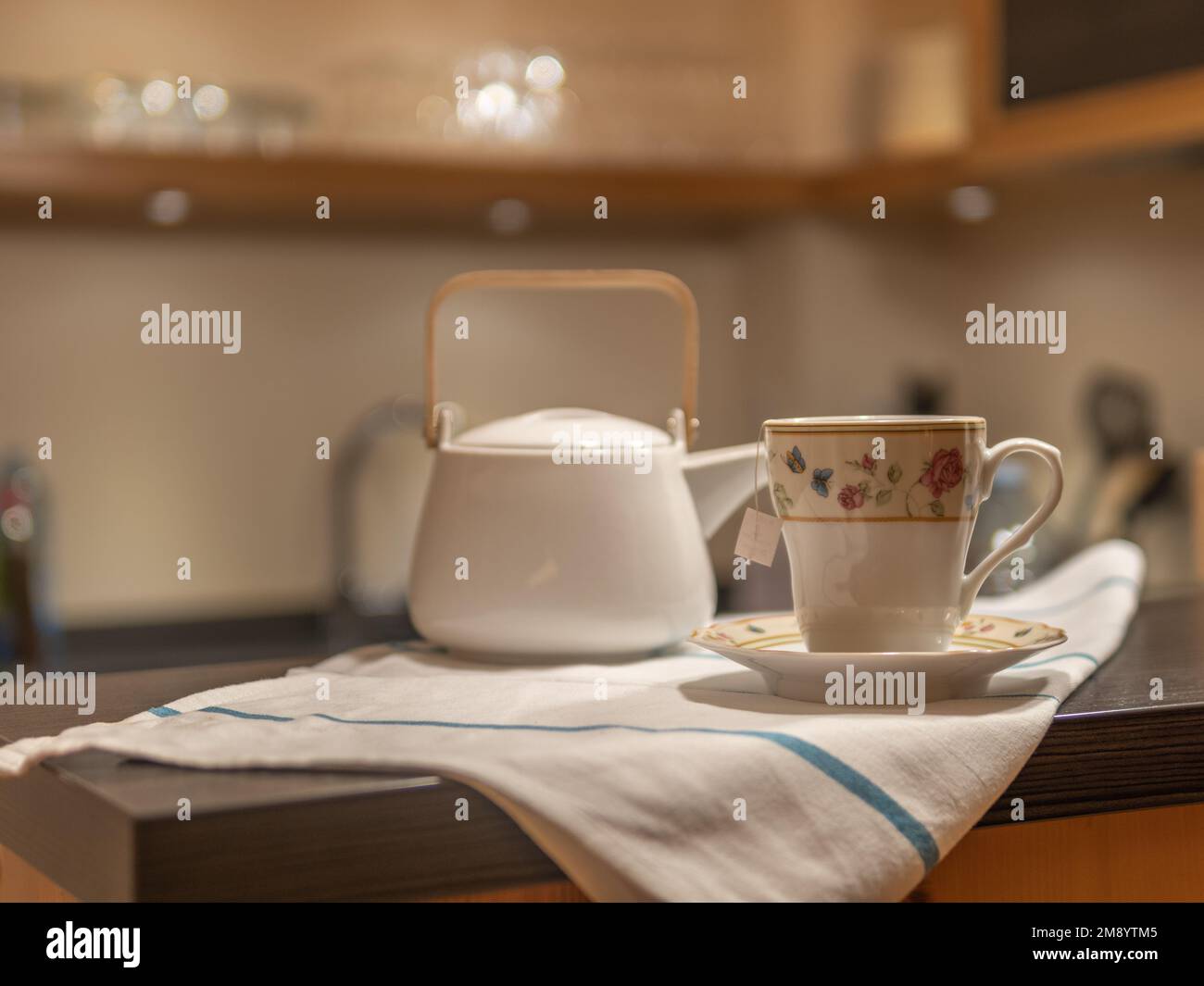 CUP OF TEA AND WHITE TEAPOT IN WARM KITCHEN. HOMELIKE. RELAXING MOMENT ...