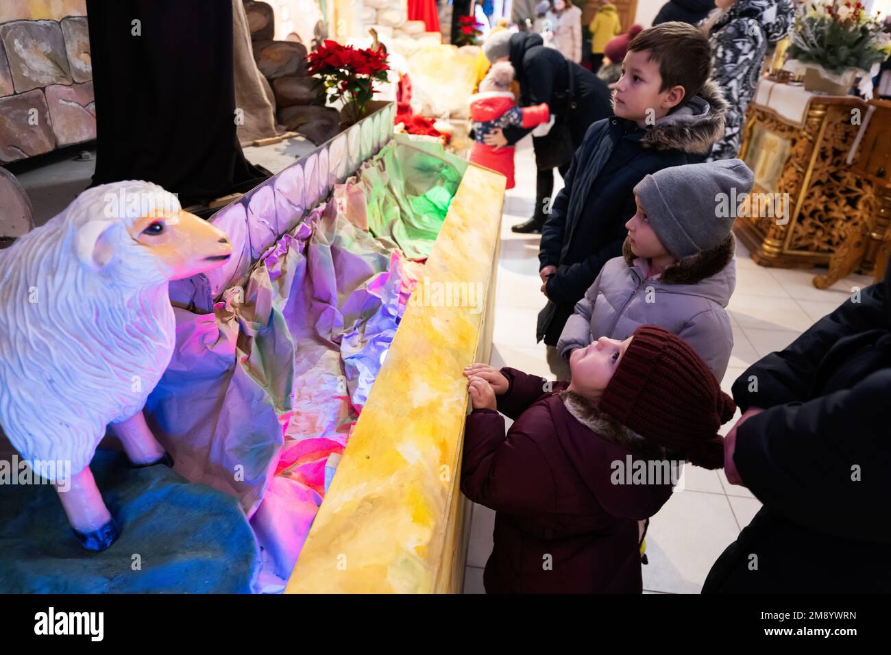 Three children looking in Christmas nativity crib scene in church Stock ...