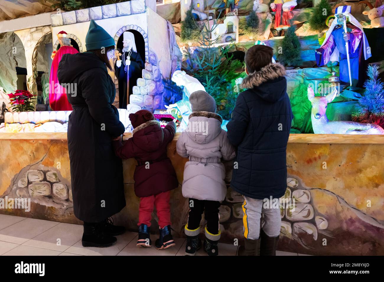 Mother with three children visit Christmas nativity crib scene in ...