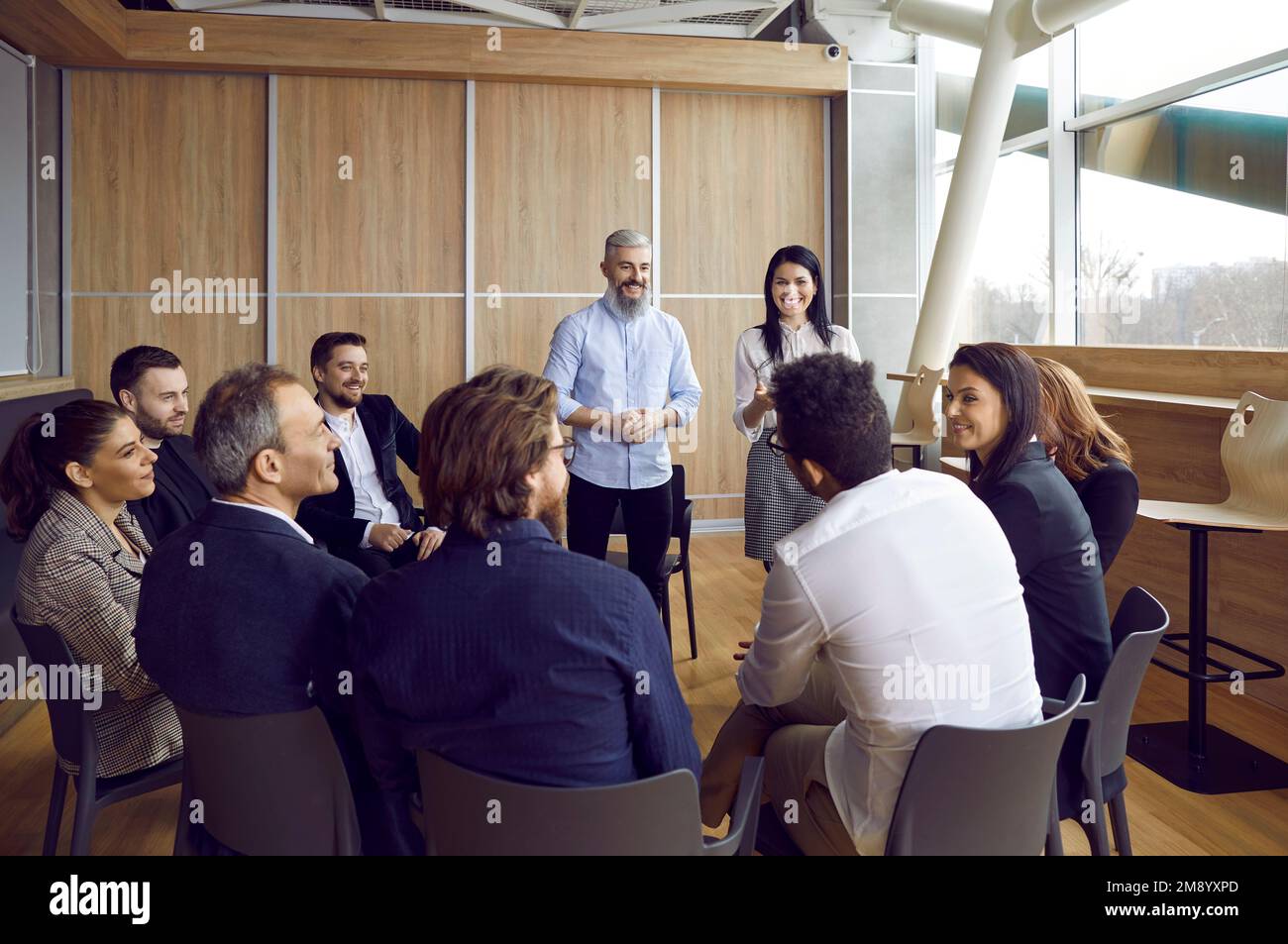 Business coach and psychologist talk to people sitting in circle during ...