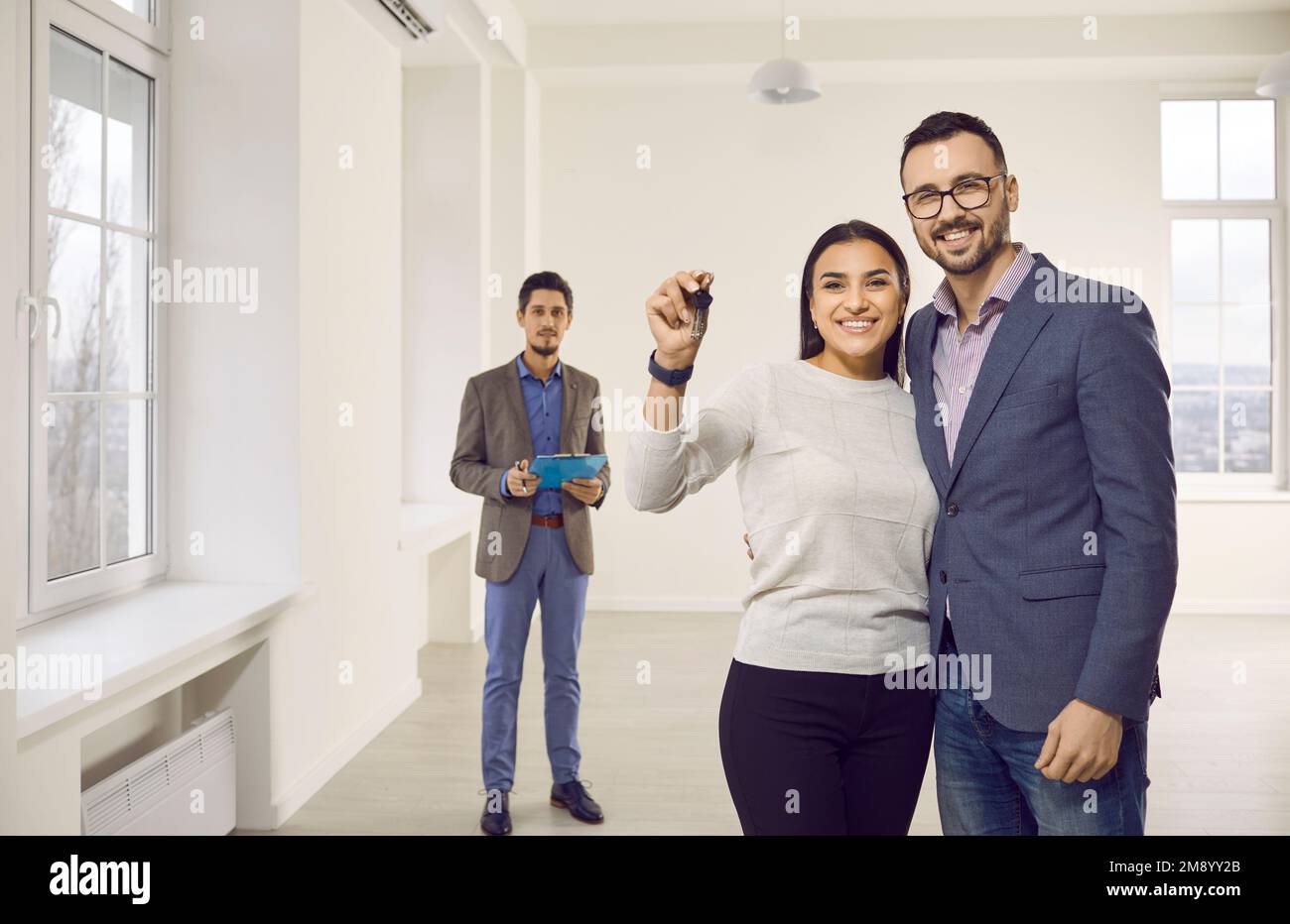 Happy young family couple showing key to house or apartment they are ...