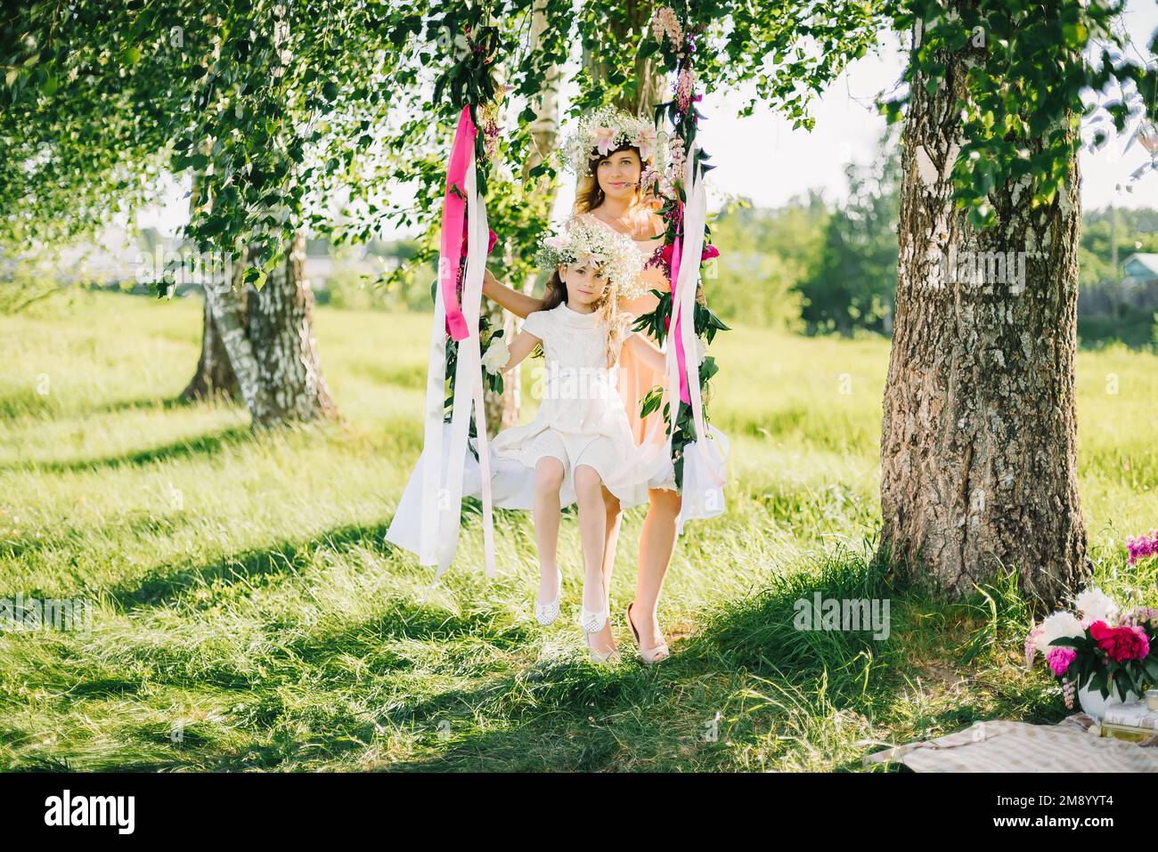 happy mother and daughter swinging on the swings decorated Sunny summer day Stock Photo - Alamy