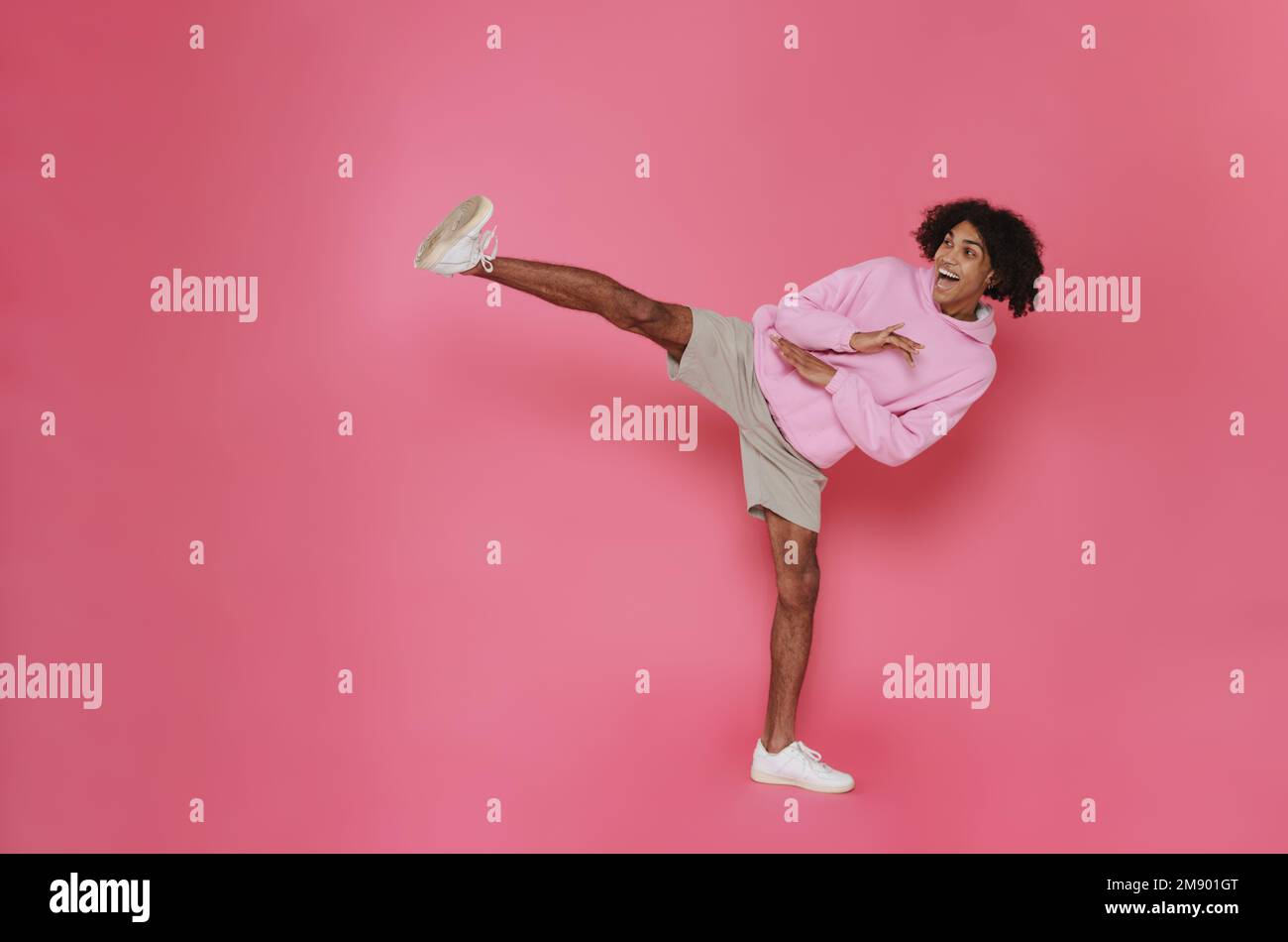 Young smiling handsome stylish latin curly man showing fighting pose ...
