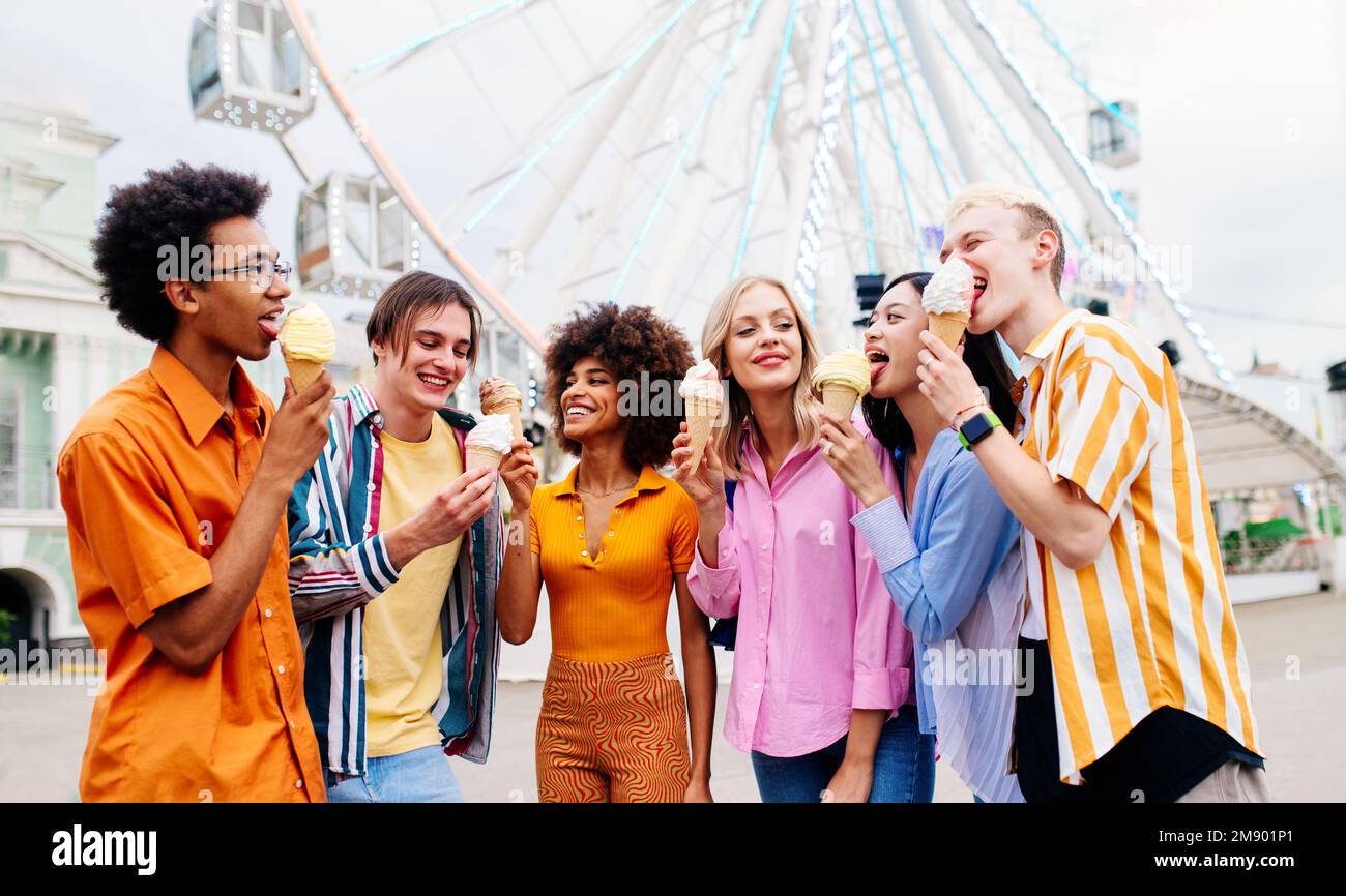 Multiracial young people together meeting at amusement park and eating ...