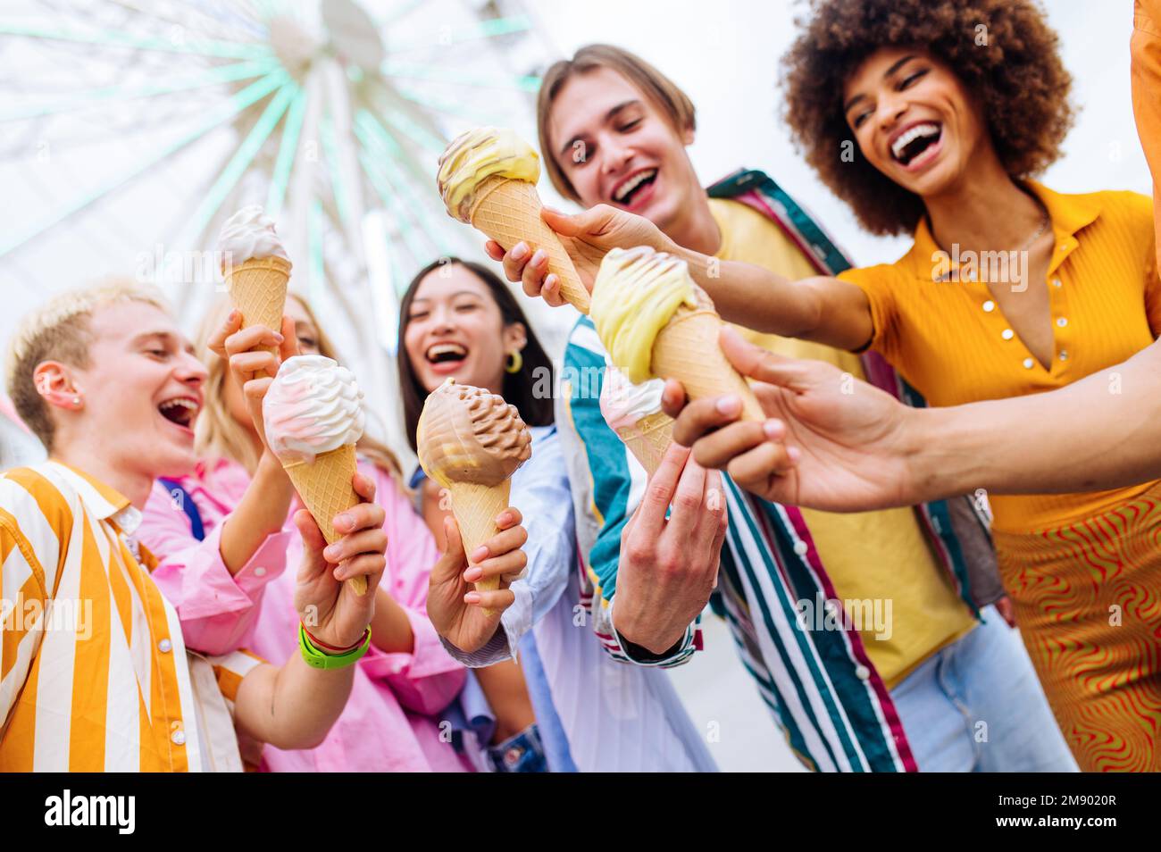 Multiracial young people together meeting at amusement park and eating ...