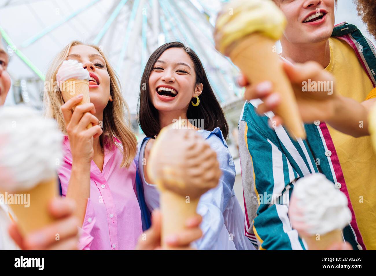 Multiracial young people together meeting at amusement park and eating ...