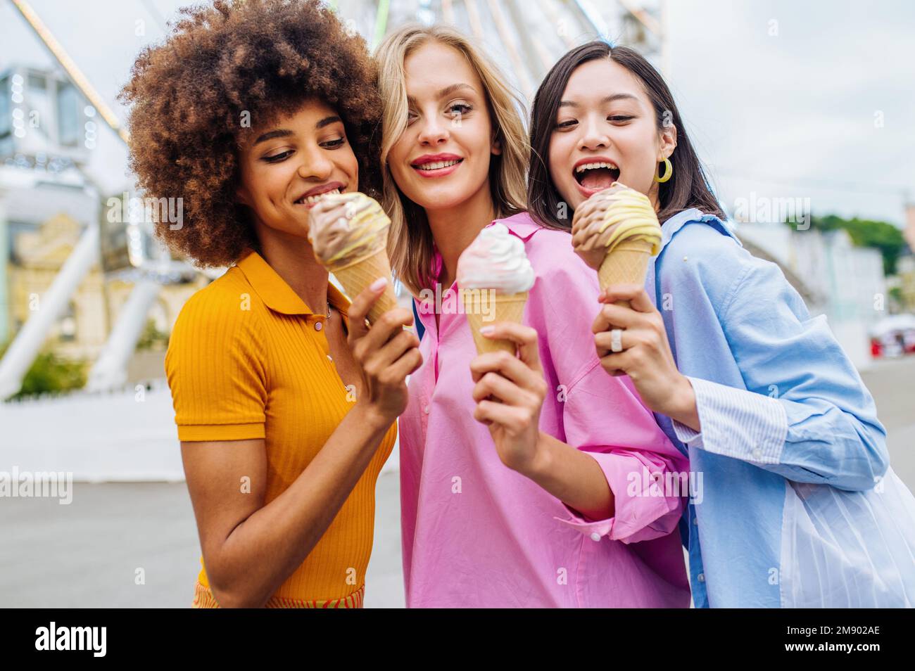 Multiracial young people together meeting at amusement park and eating ...