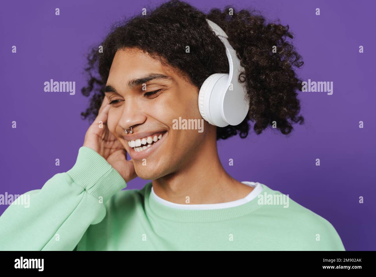 Young caribbean man laughing while listening music with headphones ...