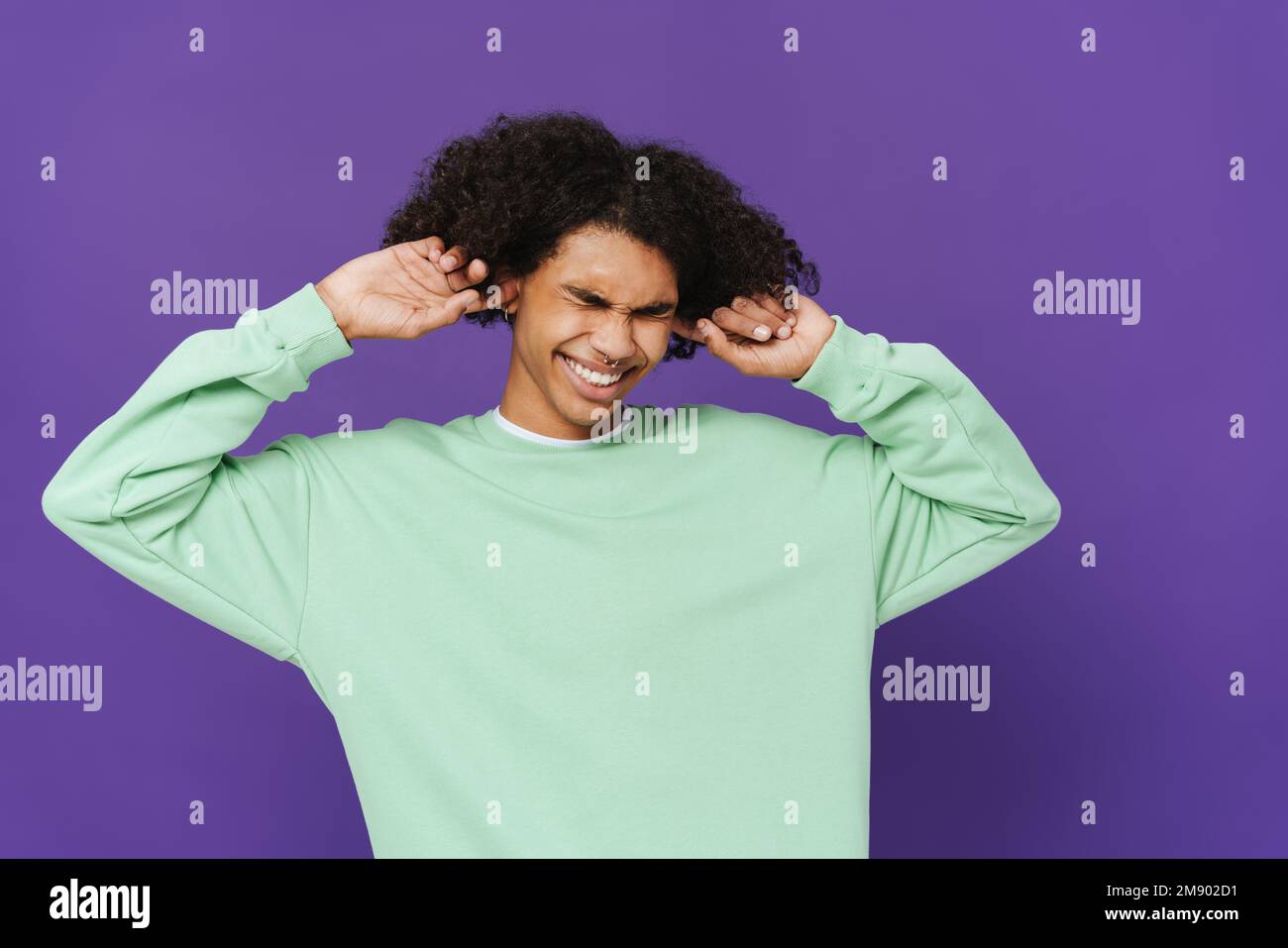 Young caribbean man with piercing plugging his ears isolated over ...