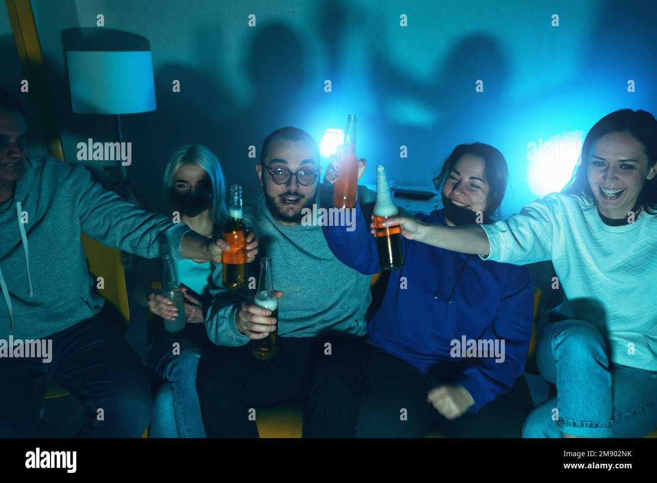 Friends watching tv in living room and drinking beer, screaming ...