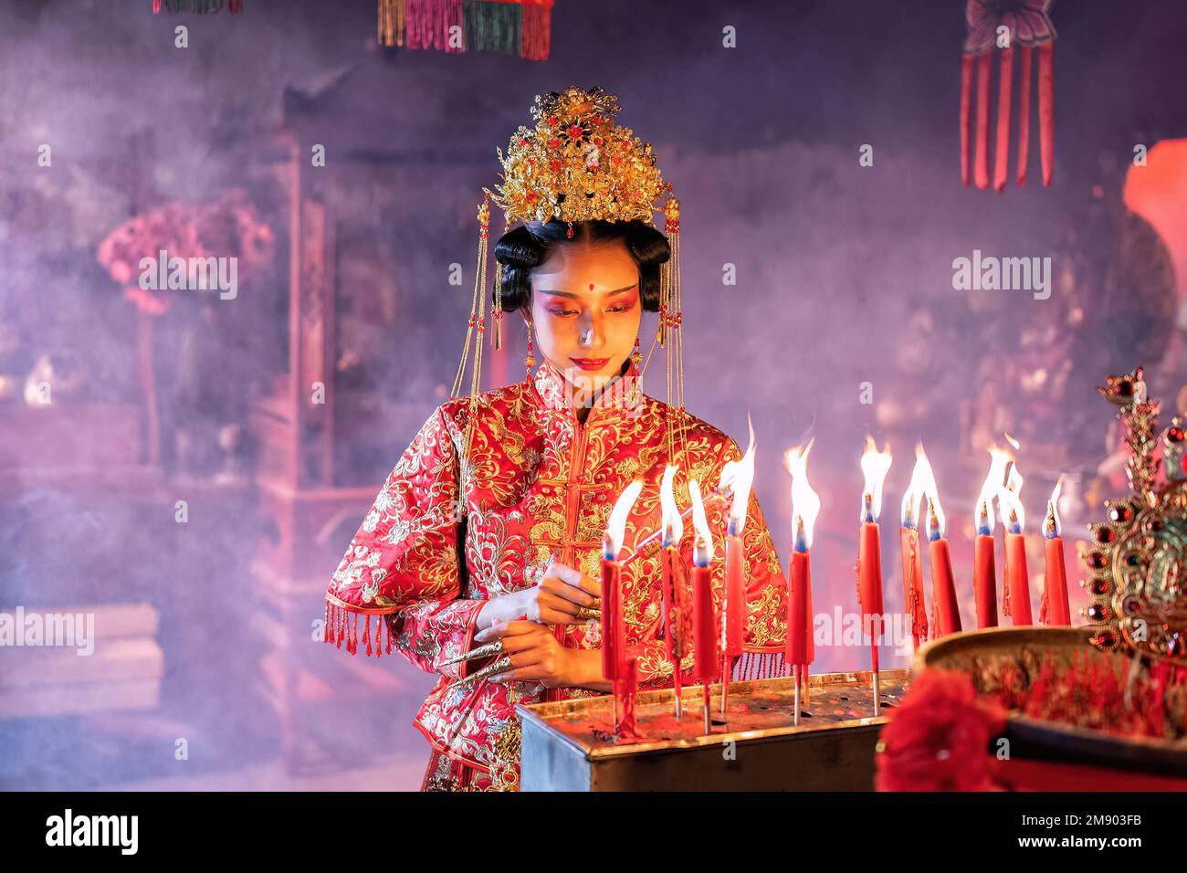 Woman traditional dress in Chinese shrine light up candle joss stick ...