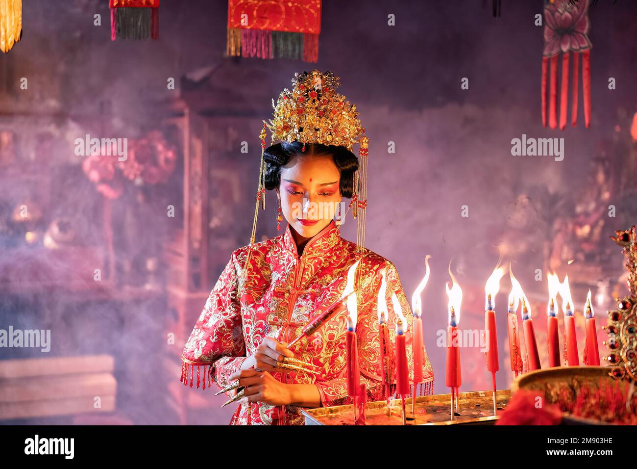 Woman traditional dress in Chinese shrine light up candle joss stick ...