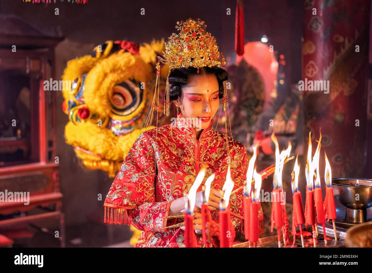 Woman traditional dress in Chinese shrine light up candle joss stick ...
