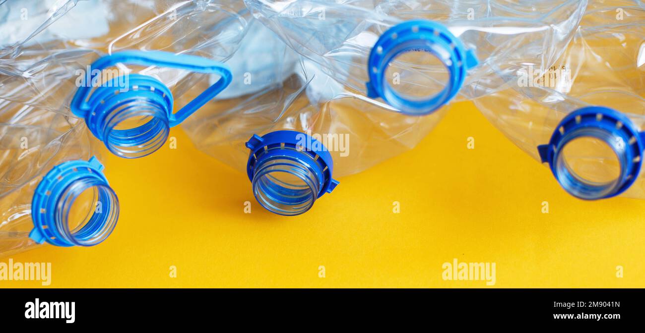 a lot of plastic empty rumpled used bottles on a yellow background ...