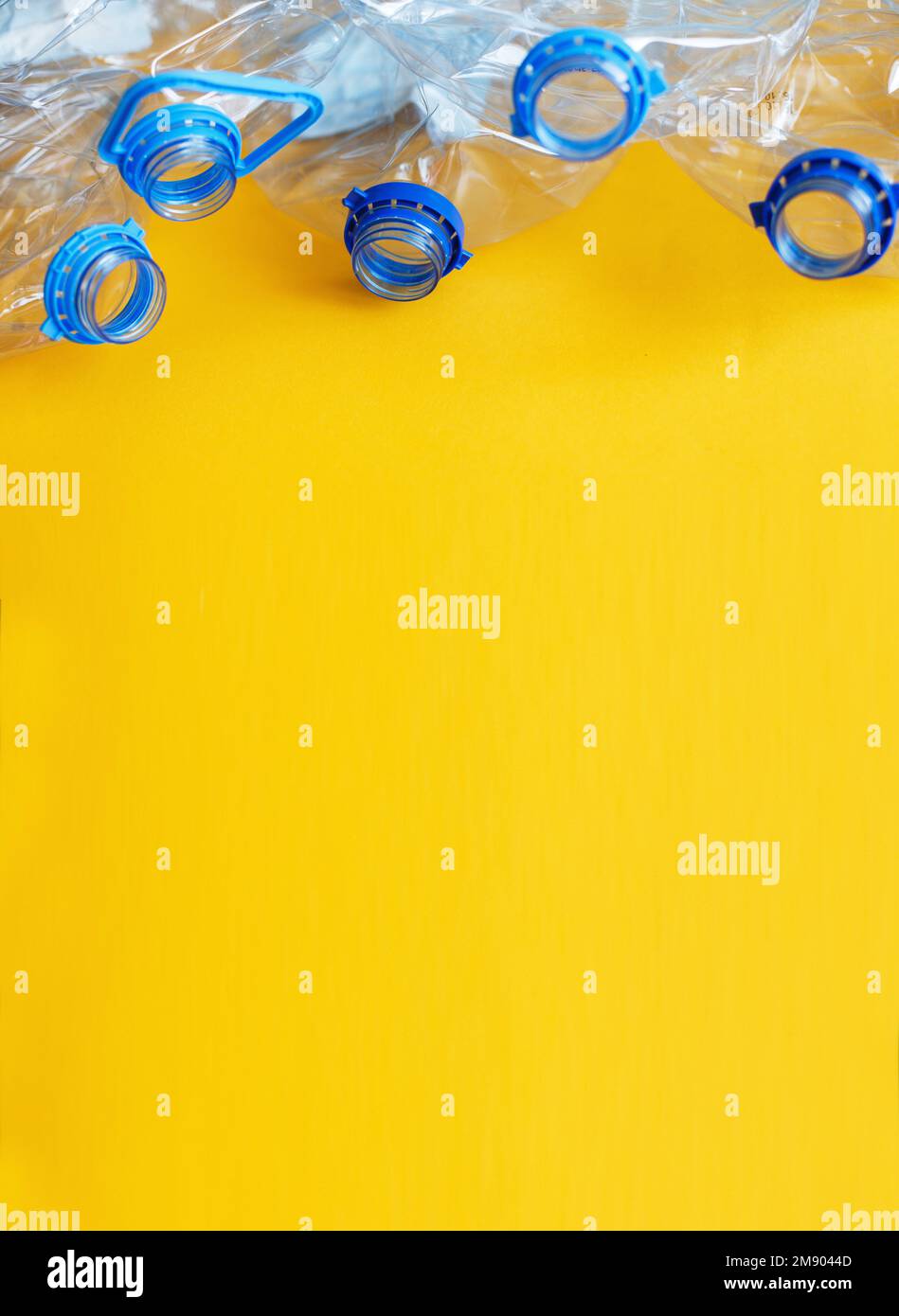 a lot of plastic empty rumpled used bottles on a yellow background ...