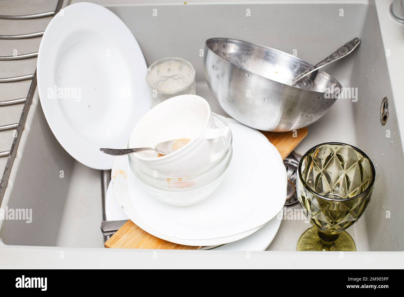 Pile of dirty dishes like plates, cutlery in the grey modern granite ...
