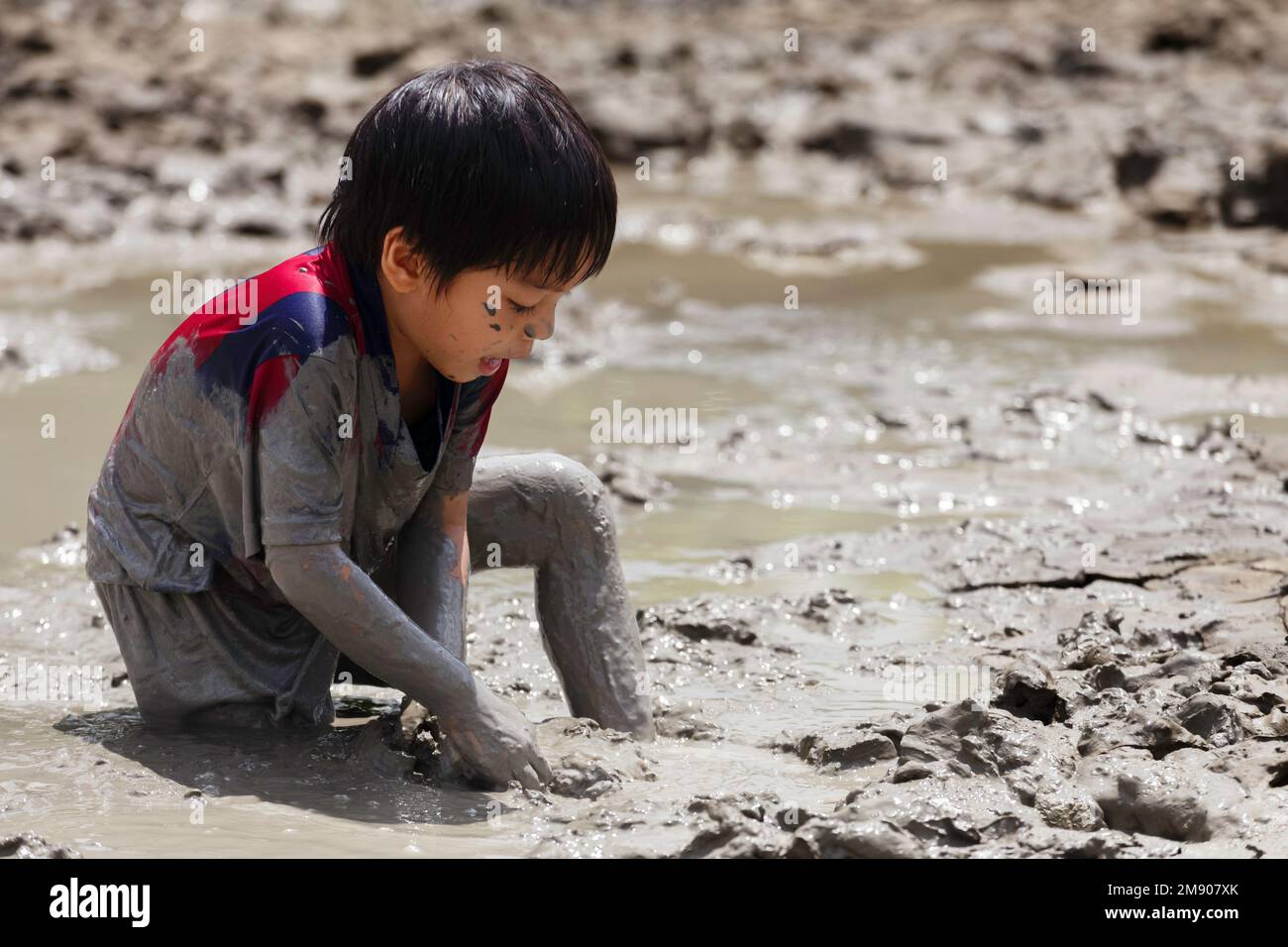 cute happy asian little boy enjoying to play in the mud at playground ...