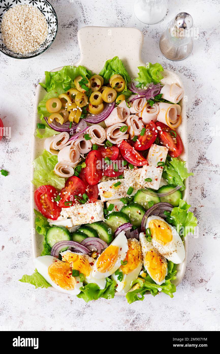Healthy cobb salad with ham, cucumber, tomato, olives, feta cheese and ...