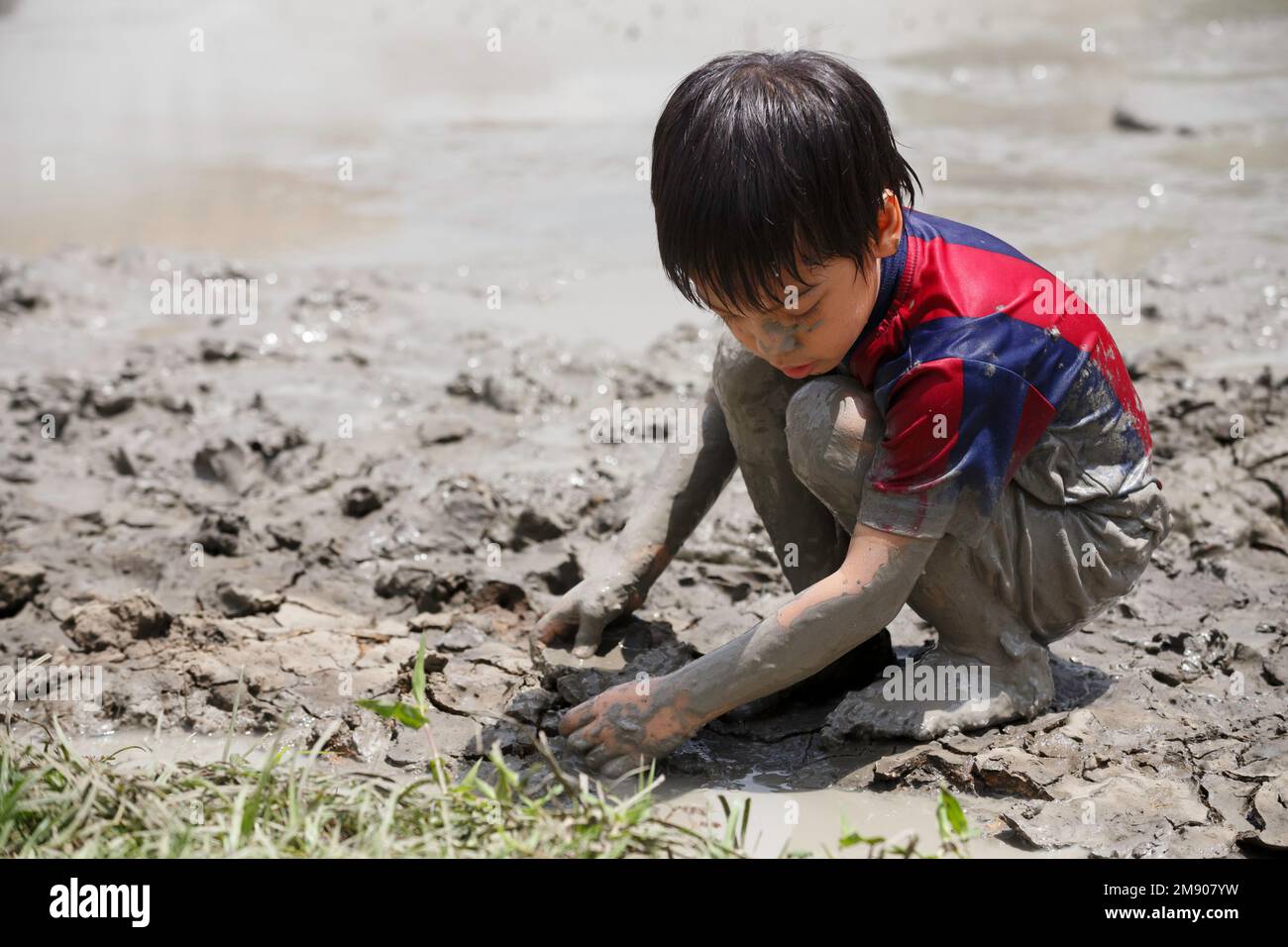 cute happy asian little boy enjoying to play in the mud at playground ...