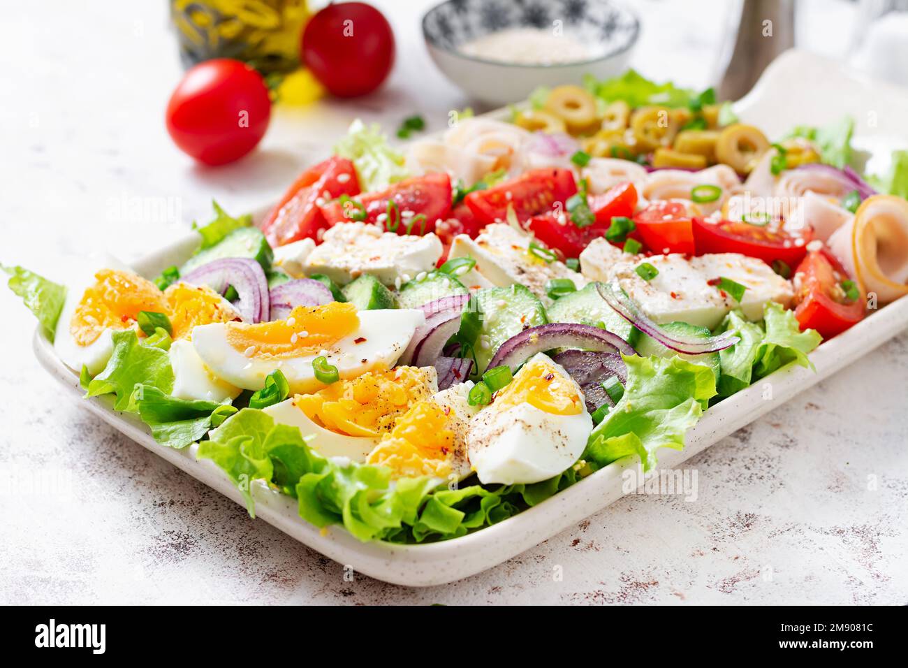 Healthy cobb salad with ham, cucumber, tomato, olives, feta cheese and ...