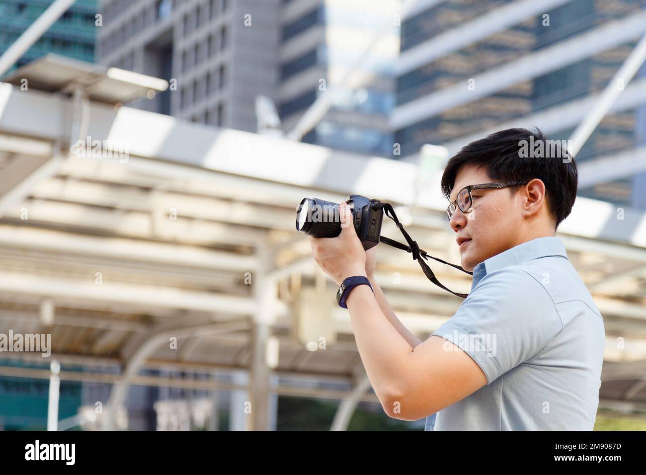 Young asian man photographer holding camera to taking picture of city ...