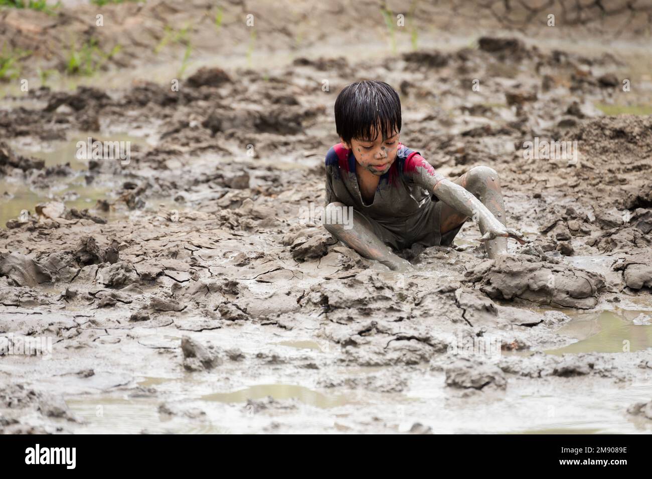cute happy asian little boy enjoying to play in the mud at playground ...