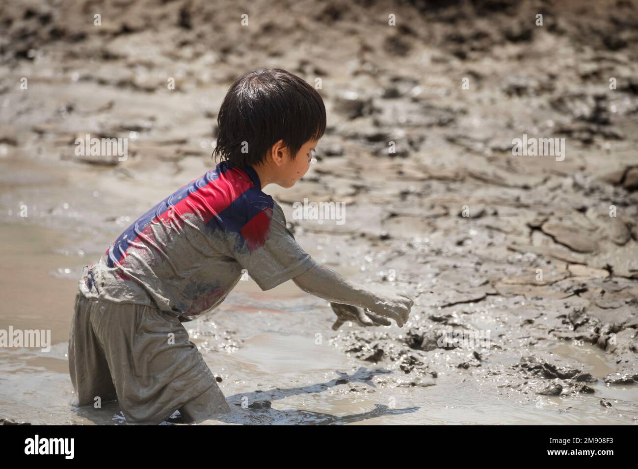 cute happy asian little boy enjoying to play in the mud at playground ...