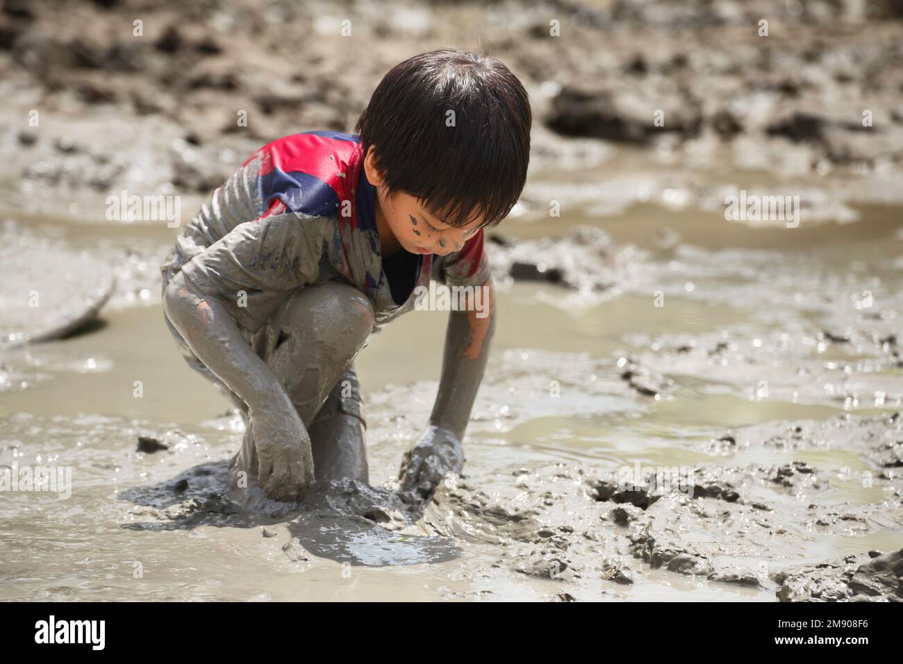 cute happy asian little boy enjoying to play in the mud at playground ...