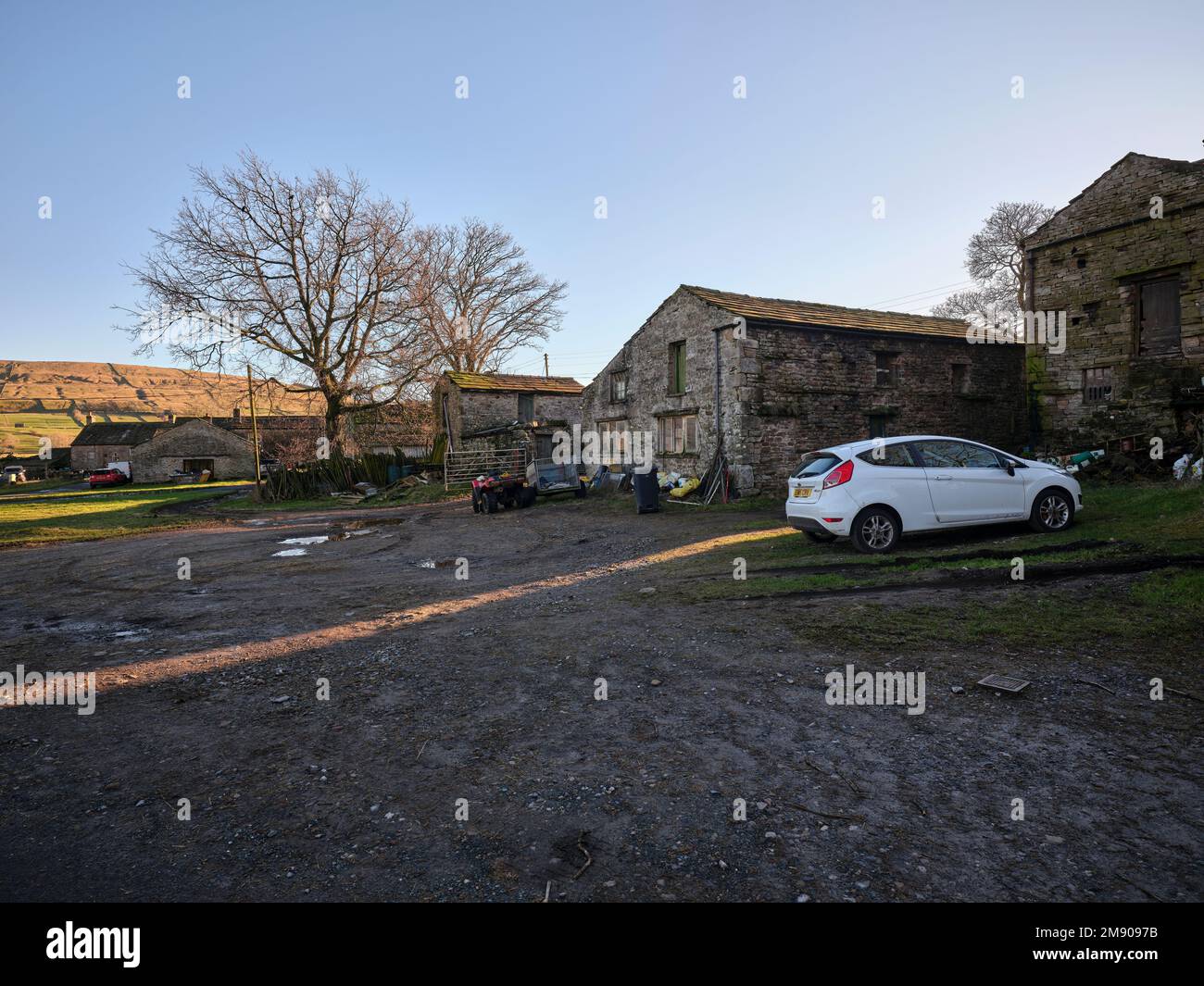 Cluster of farm buildings with bright blue sky, distant hills and rough ...